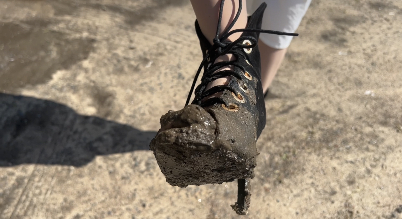 A girl in high-heeled shoes with exposed toes walks through the mud and ...